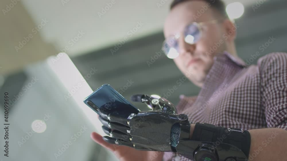 Man with a bionic futuristic arm uses smartphone. A male with a ...