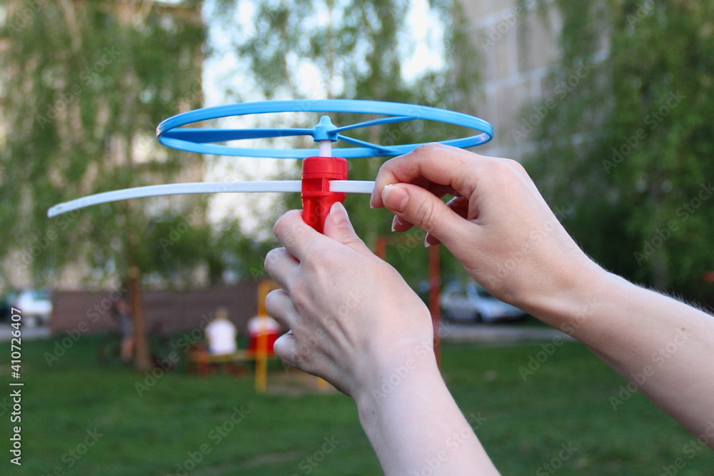 Blue propeller toy start with red handle in white woman hands close up ...