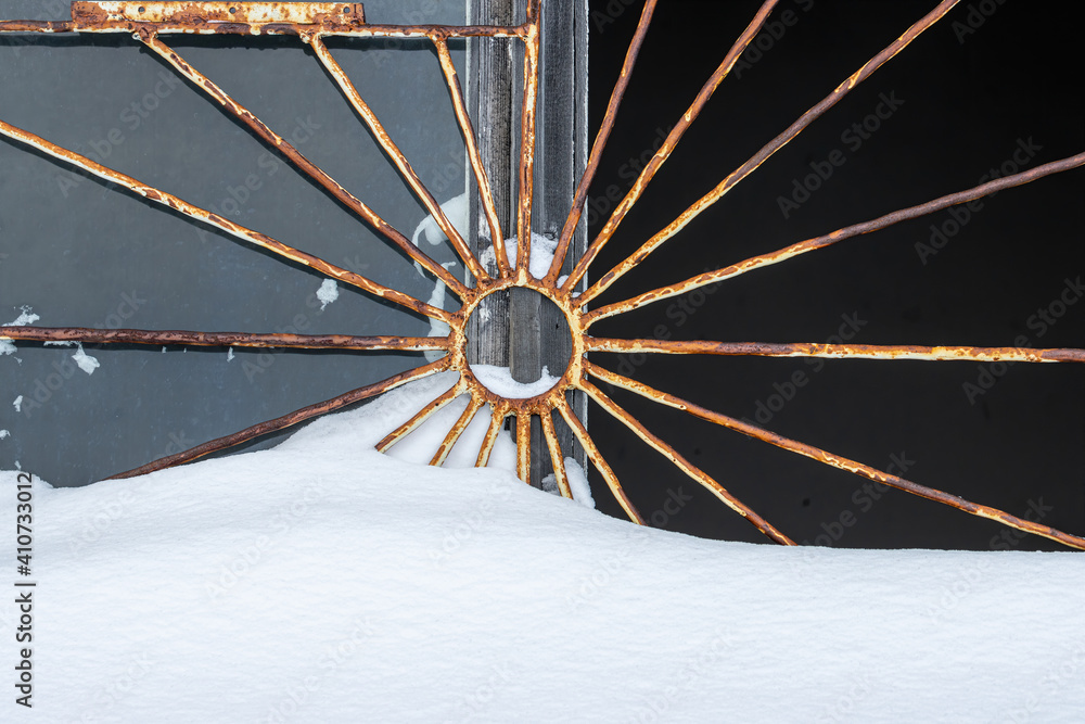 Rusty metal window grill in the form of rays. Window covered with snow ...