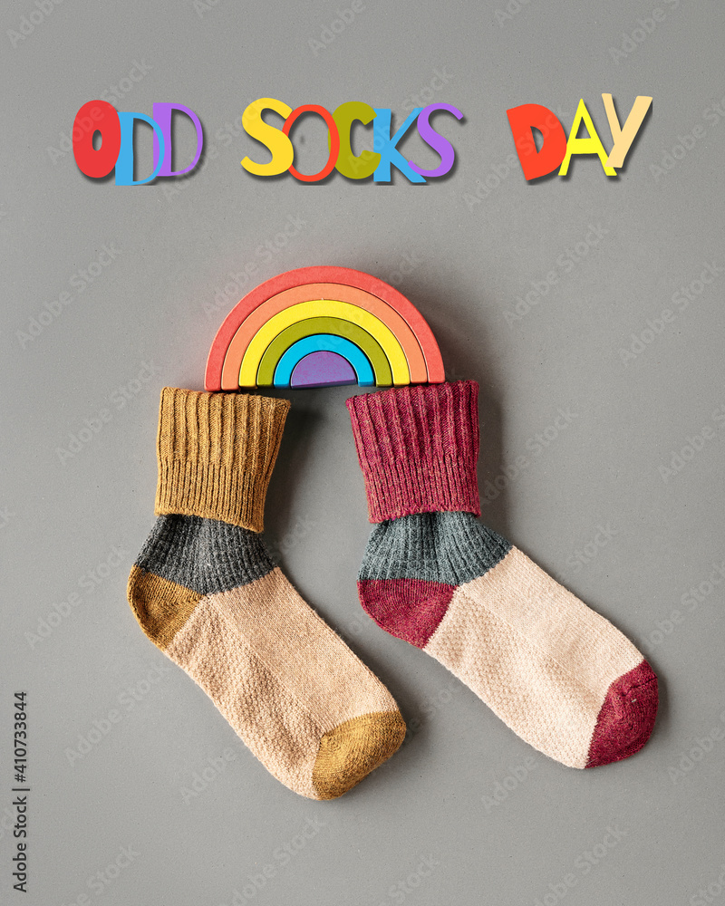 Odd Socks Day text. Mismatched socks and rainbow toy. Social initiative against bullying in ...