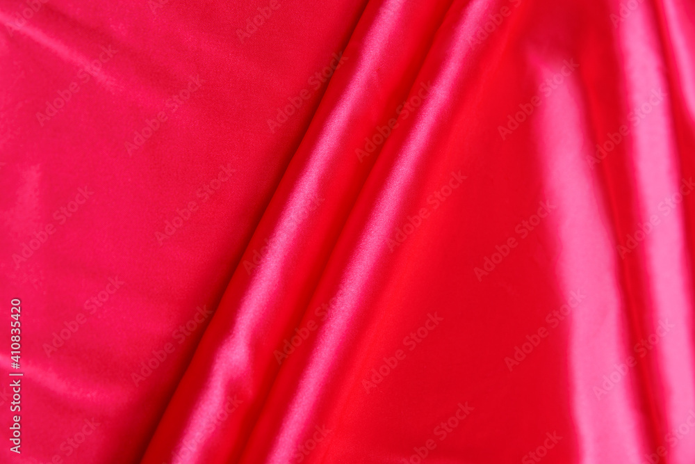 Colored red textile satin fabric folded in folds and waves with ...