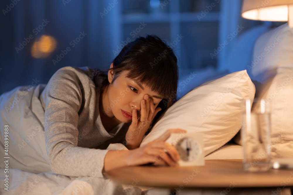 people, bedtime and rest concept - sleepy asian woman with clock lying ...