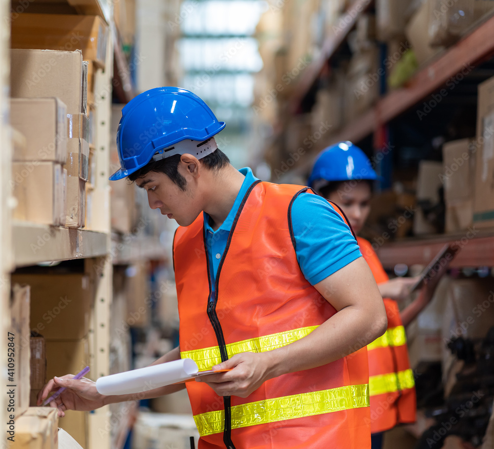 Asian male and female warehouse worker working with clipboard for ...