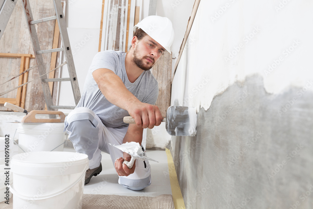 man plasterer construction worker at work, takes plaster from bucket ...