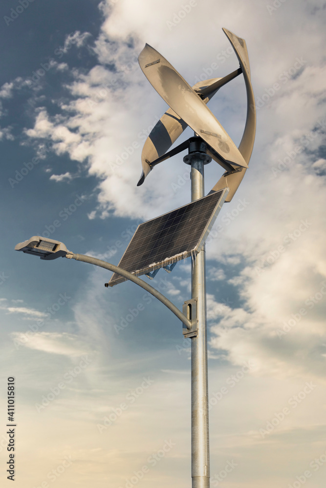 A modern vertical wind turbine with a solar panel on a light pole ...