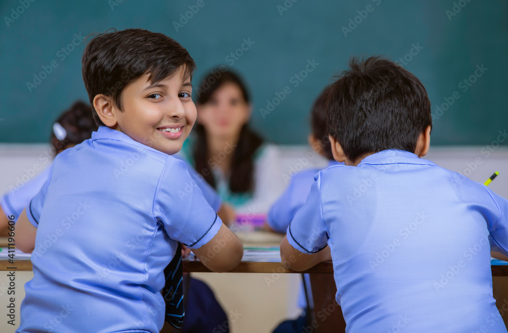 school boy smiling while teacher is sitting in class Stock Photo ...