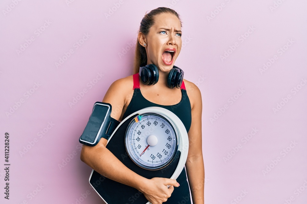 Beautiful young blonde sporty woman holding weight machine to balance ...