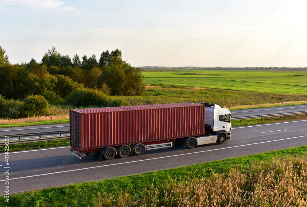 Semi truck transporting sea container on highway on sunset background ...