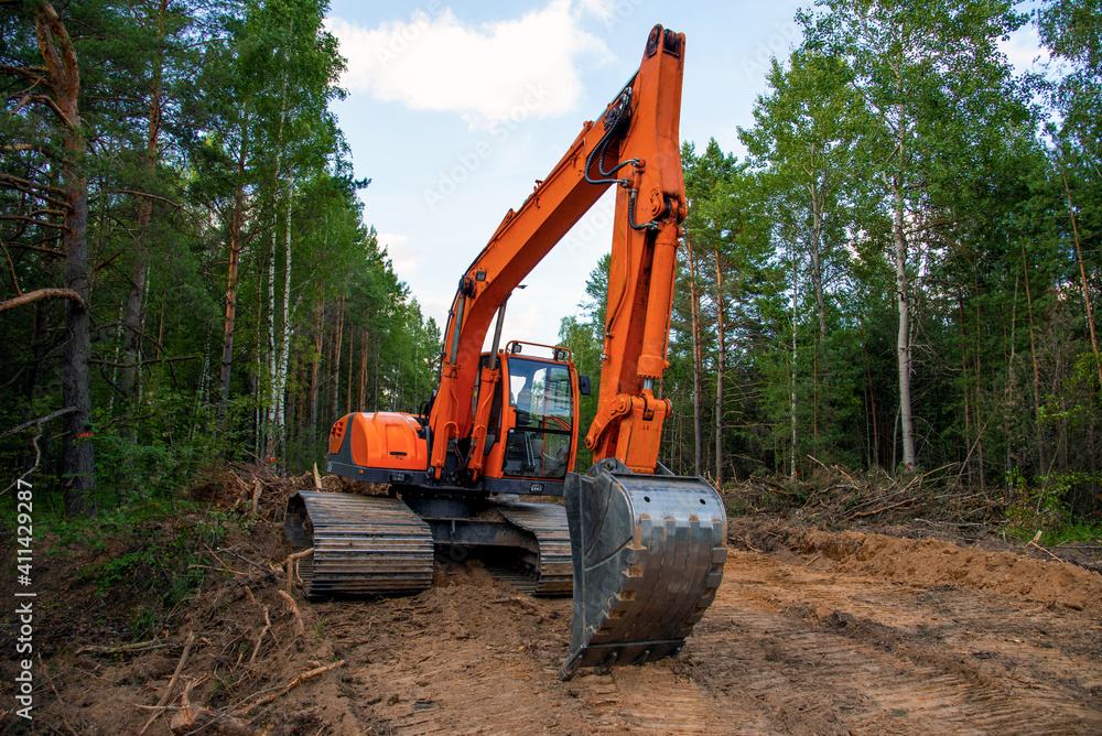 Excavator clearing forest for new development. Orange Backhoe modified ...