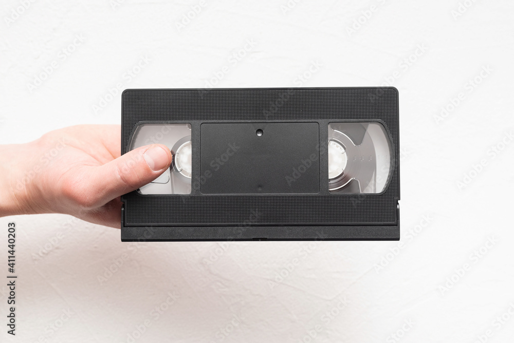 Old black vhs video tape in the male hands on the white background ...