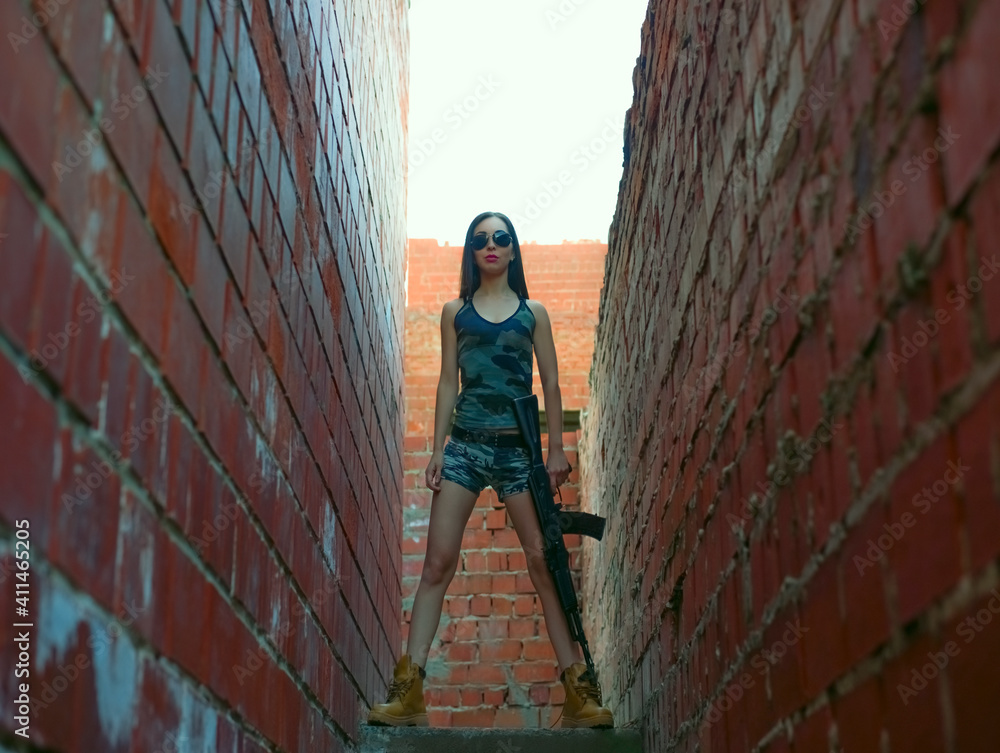 Soldier asian woman holding machine gun and standing between red brick ...