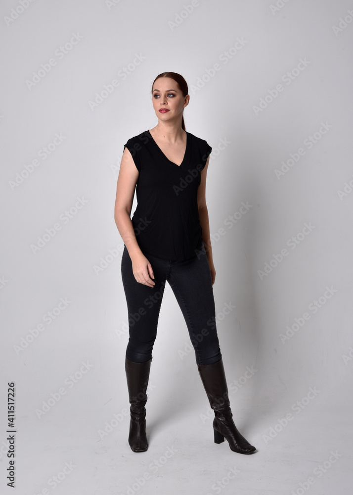 Simple full length portrait of woman with red hair in a ponytail ...