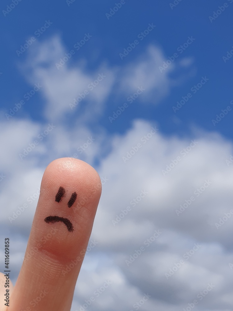 Sad-faced finger drawn, sky in the background. Related to sadness ...