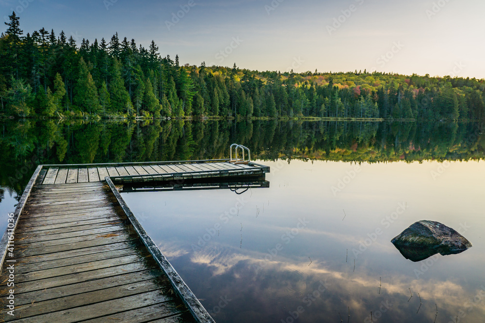 Dock ladder leading to a very tranquil lake at dusk, the sun is setting ...