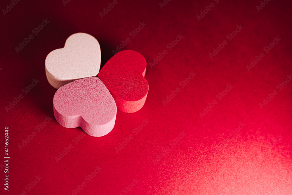 Top view of a three little hearts of sponges on a red background. There ...
