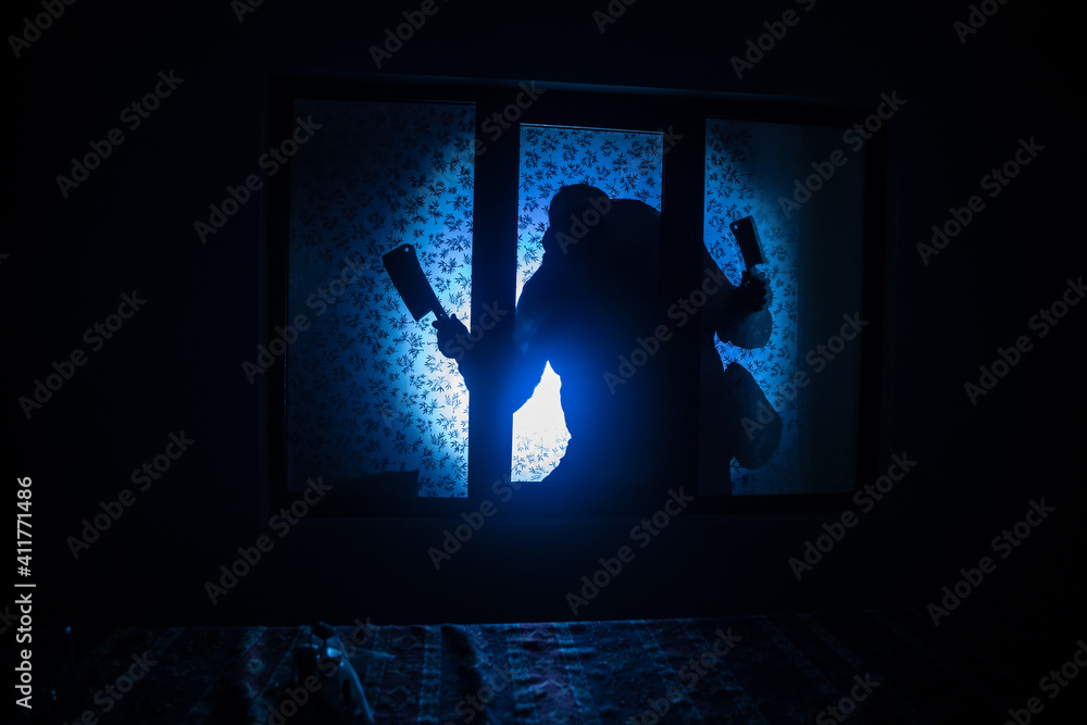Silhouette of an unknown shadow figure on a door through a closed glass ...