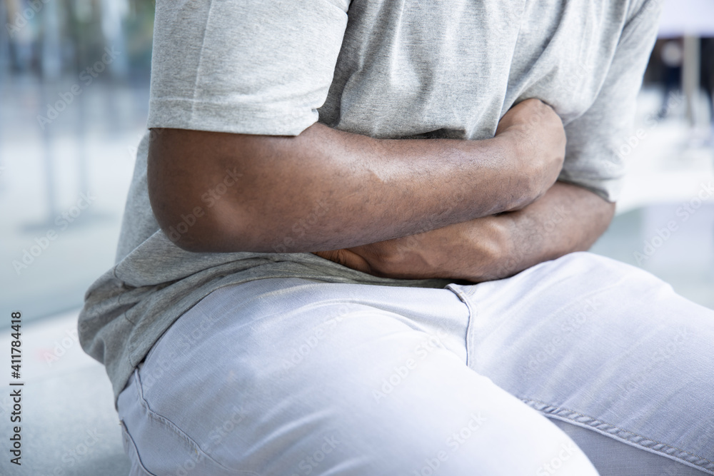 Balck African man with stomach ache; young adult African man suffering ...