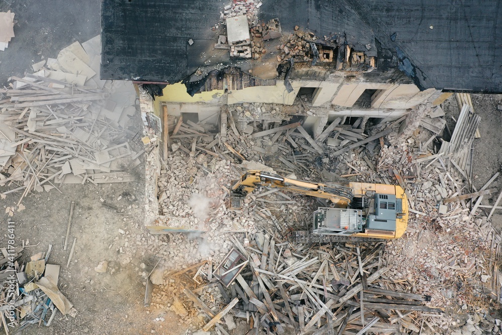 Yellow excavator destroys building. Heavy duty machine is demolishing a ...