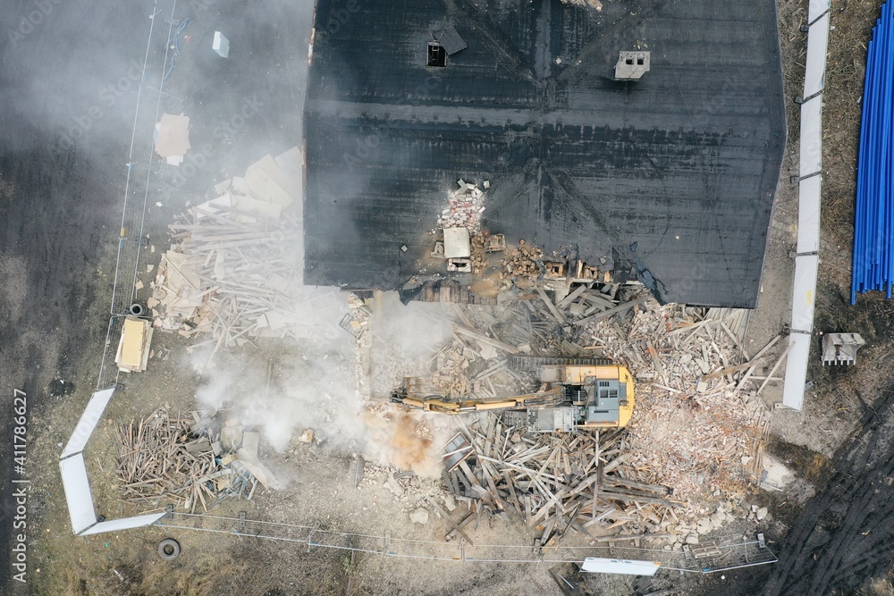 Yellow excavator destroys building. Heavy duty machine is demolishing a ...