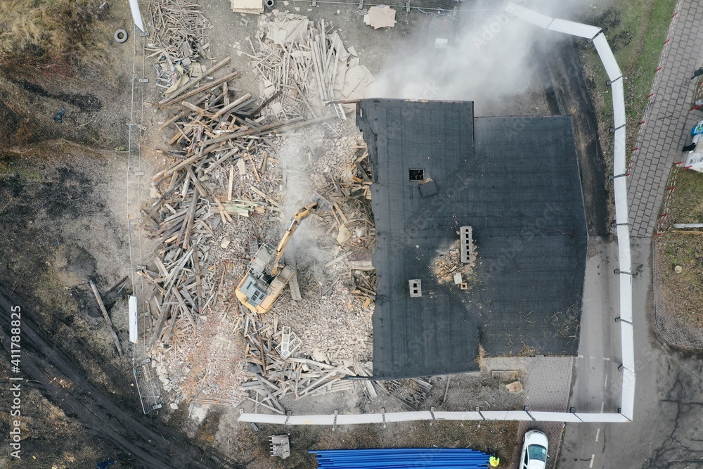 Yellow excavator destroys building. Heavy duty machine is demolishing a ...