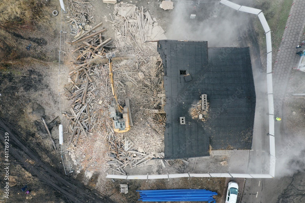 Yellow excavator destroys building. Heavy duty machine is demolishing a ...