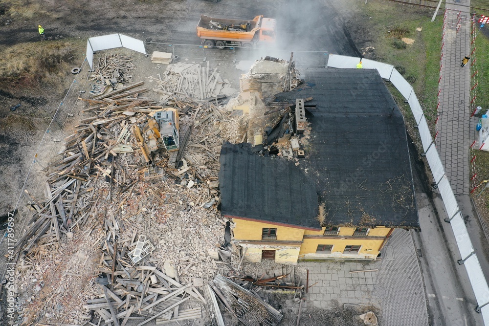 Yellow excavator destroys building. Heavy duty machine is demolishing a ...