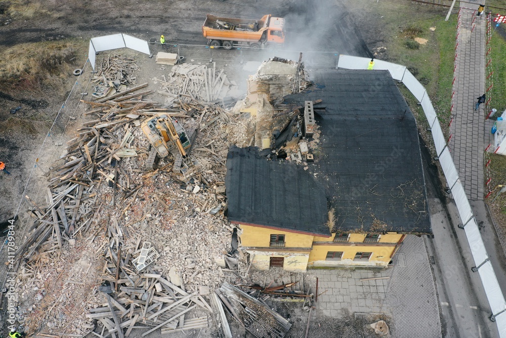 Yellow excavator destroys building. Heavy duty machine is demolishing a ...