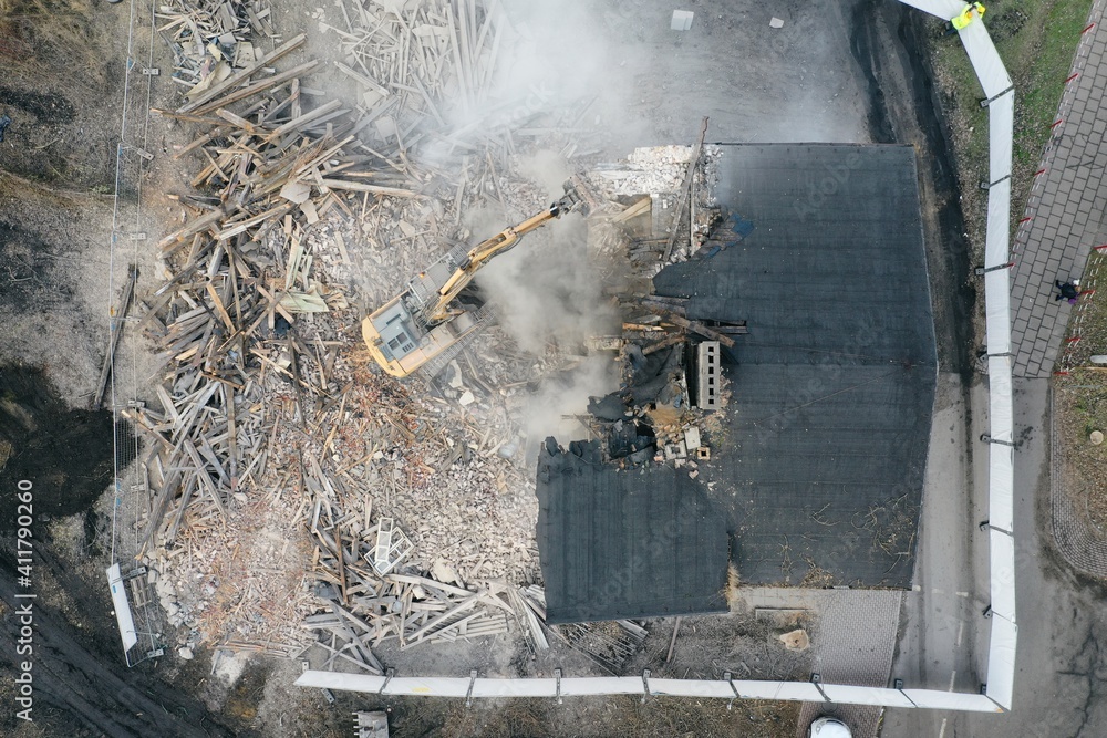 Yellow excavator destroys building. Heavy duty machine is demolishing a ...