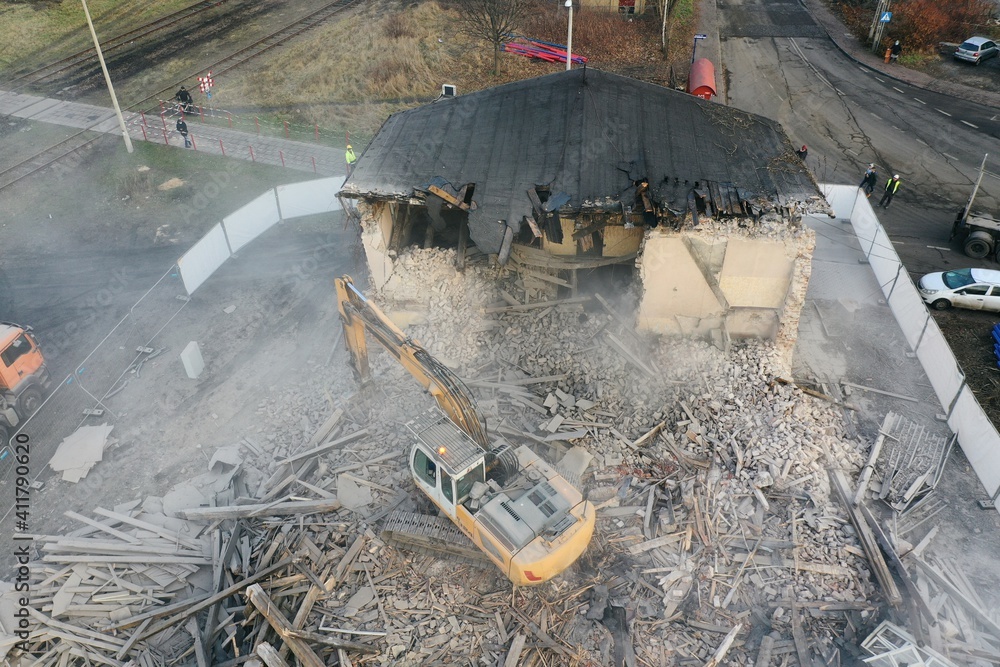 Yellow excavator destroys building. Heavy duty machine is demolishing a ...