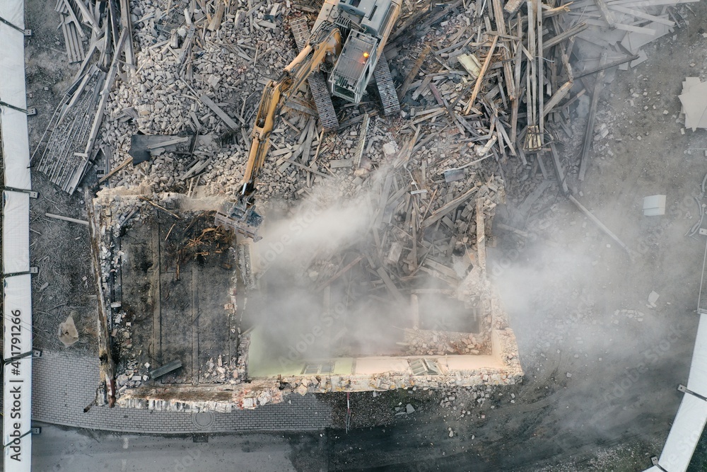 Yellow excavator destroys building. Heavy duty machine is demolishing a ...