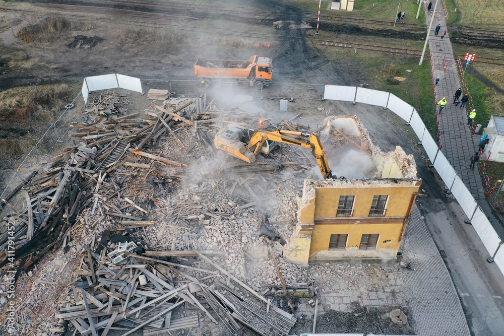 Yellow excavator destroys building. Heavy duty machine is demolishing a ...