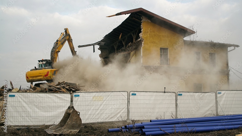 Yellow excavator destroys building. Heavy duty machine is demolishing a ...