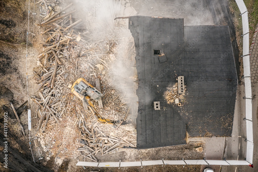 Yellow excavator destroys building. Heavy duty machine is demolishing a ...