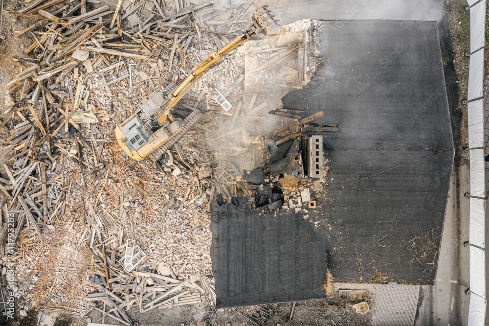 Yellow excavator destroys building. Heavy duty machine is demolishing a ...