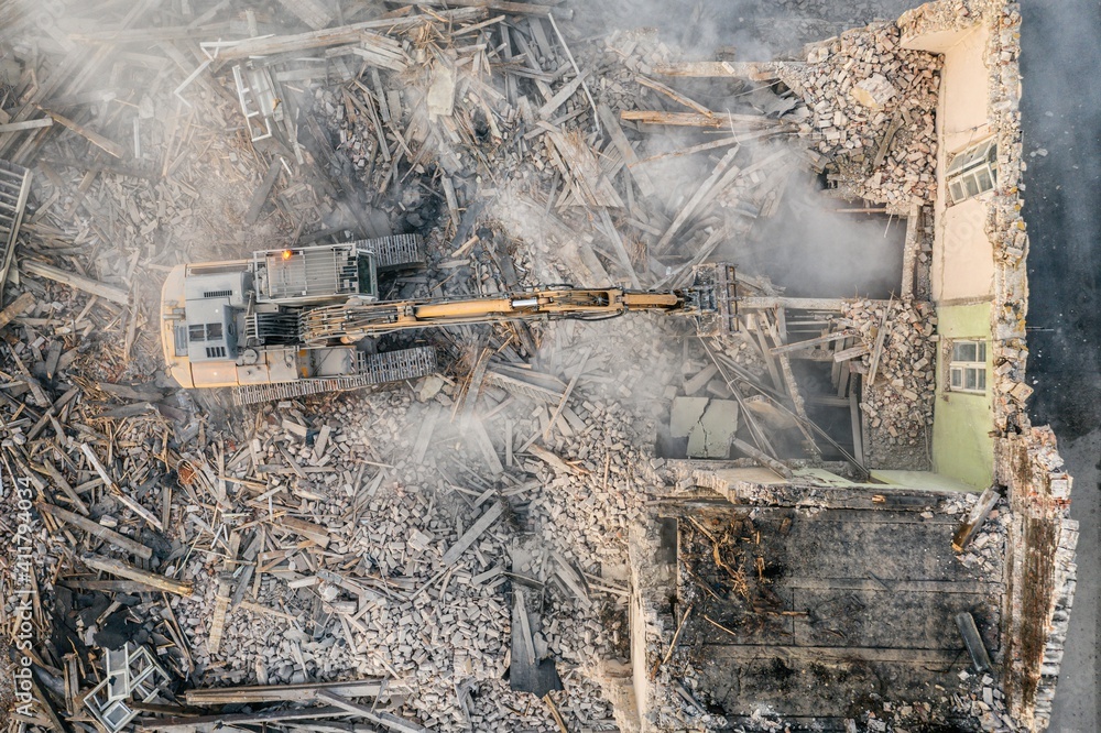 Yellow excavator destroys building. Heavy duty machine is demolishing a ...