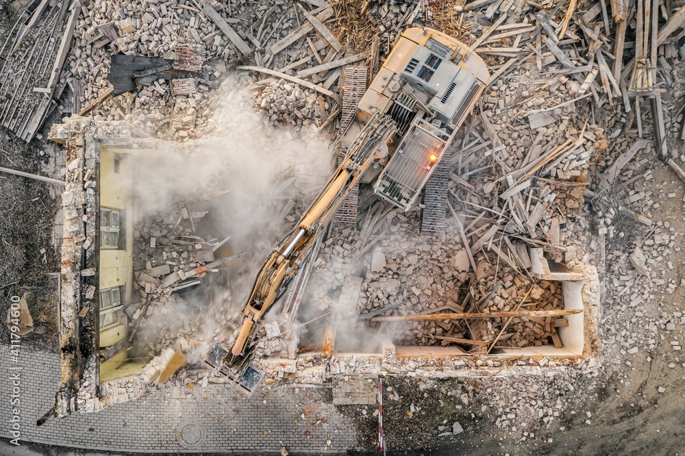 Foto de Yellow excavator destroys building. Heavy duty machine is ...