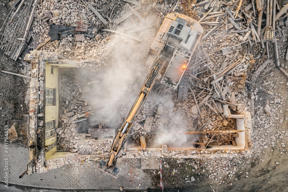 Yellow excavator destroys building. Heavy duty machine is demolishing a ...