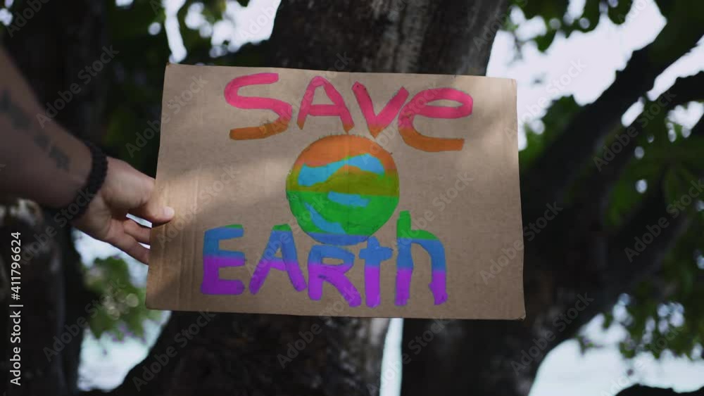Demonstration of hands holding a rainbow colored "Save the Earth ...
