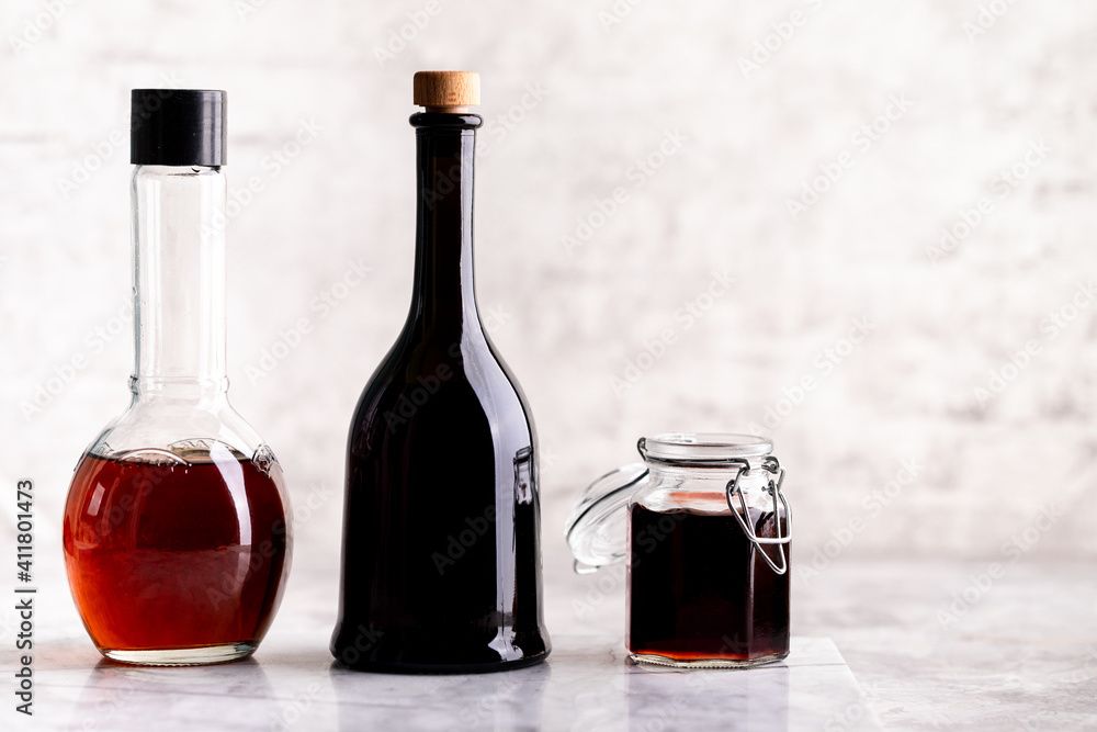 Original glass bottles with different vinegar on a marble table against ...