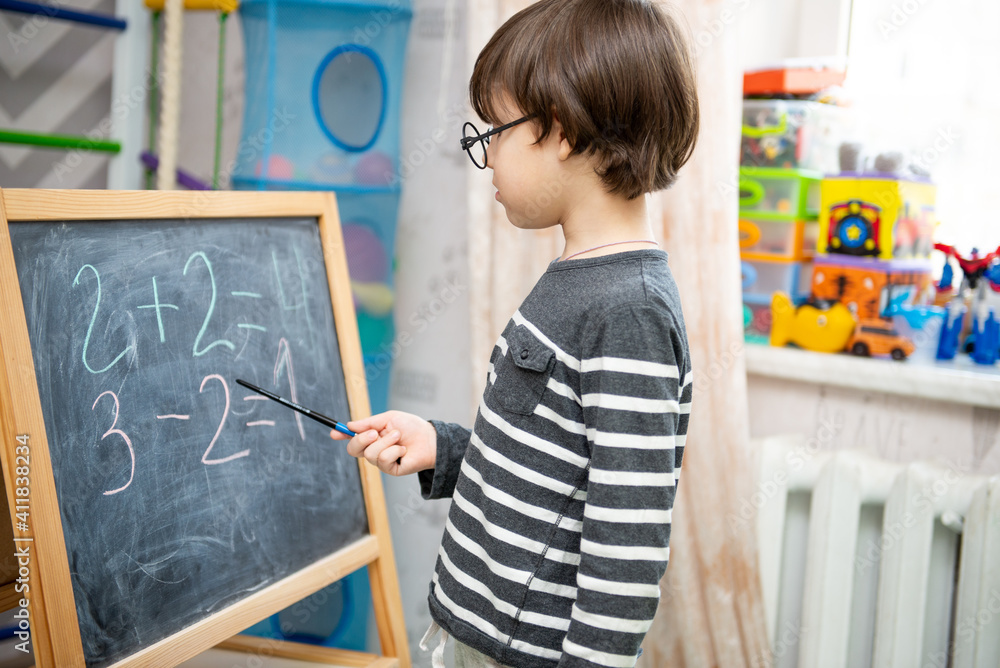 Studying at home. The kid learns to count numbers on the board ...