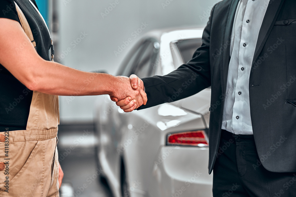 Thank you for your trust. Cropped shot of a mechanic shaking hands with ...