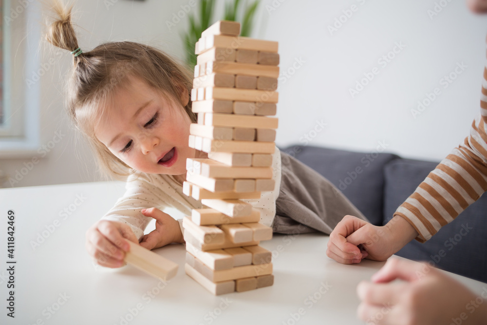 Foto de children play board game jenga. girls build tower of wooden ...