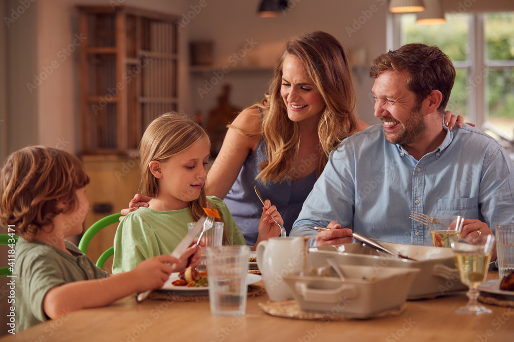 Family Sitting Around Table At Home Enjoying Meal Together Stock Photo ...