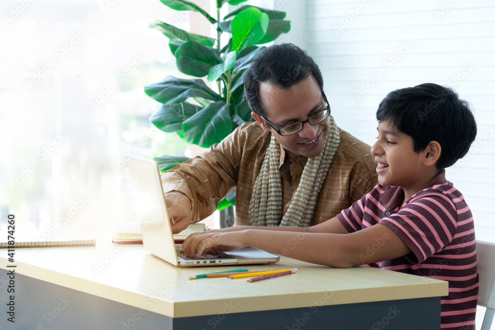 Indian father and son are happy while studying online lesson at home ...