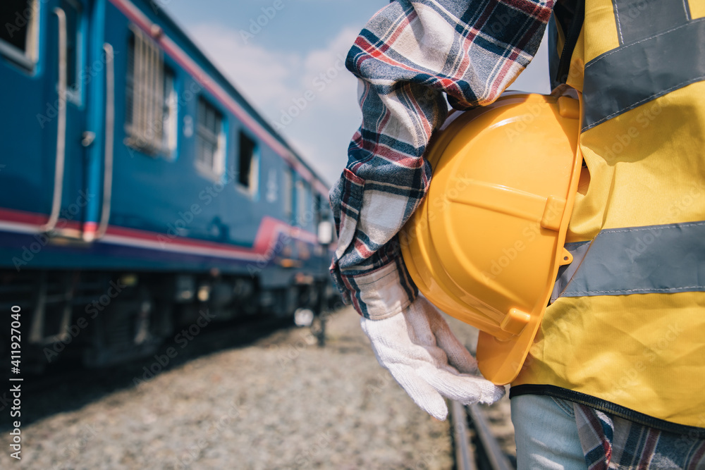 Back view of train engineering standing and holding hardhat at work ...