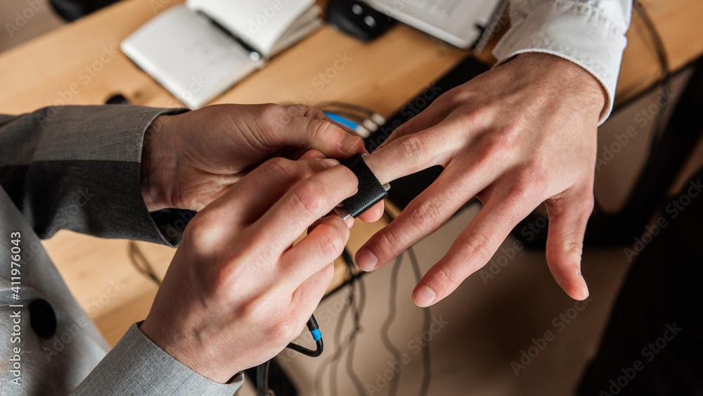 close-up, girl puts on a man's hand sensors for passing a polygraph, a ...