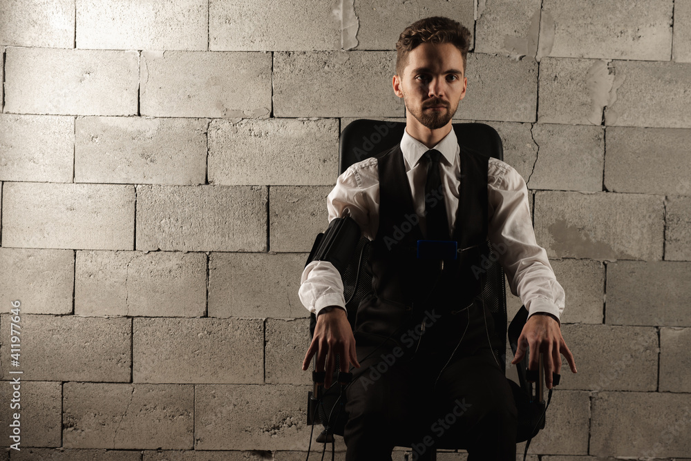 Concentrated, pensive, man in a gray room sitting on a chair, testing ...