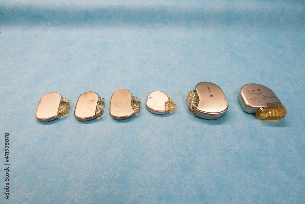 some various pacemakers and implantable defibrilators lie on a light ...