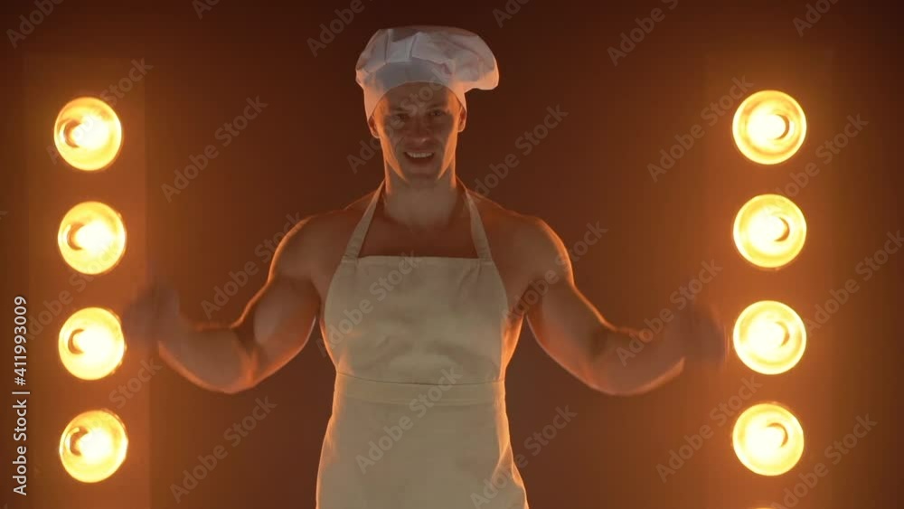Portrait of muscular chef wearing white apron and chef hat, showing ...