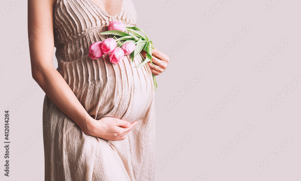 Beautiful pregnant woman with tulips flowers holds hands on belly ...